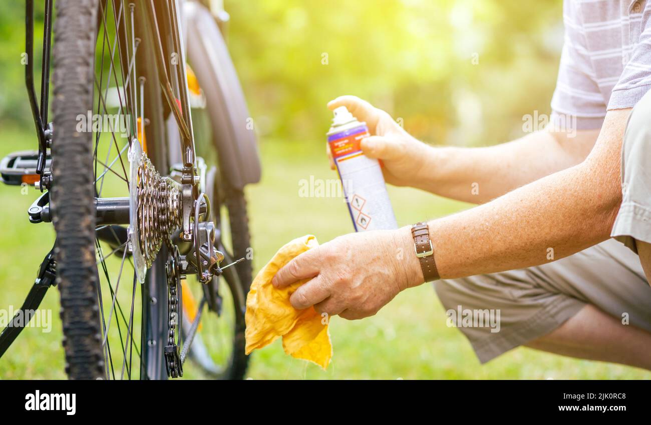 Senior man doing maintenance for his bicycle during summer time, oiling ...