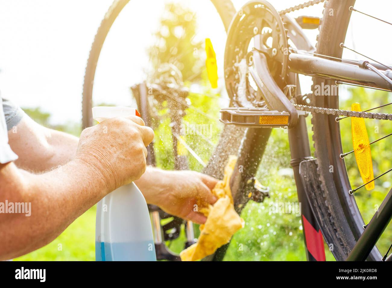 Senior man hand cleaning the bike by spray and a rag, doing maintenance ...