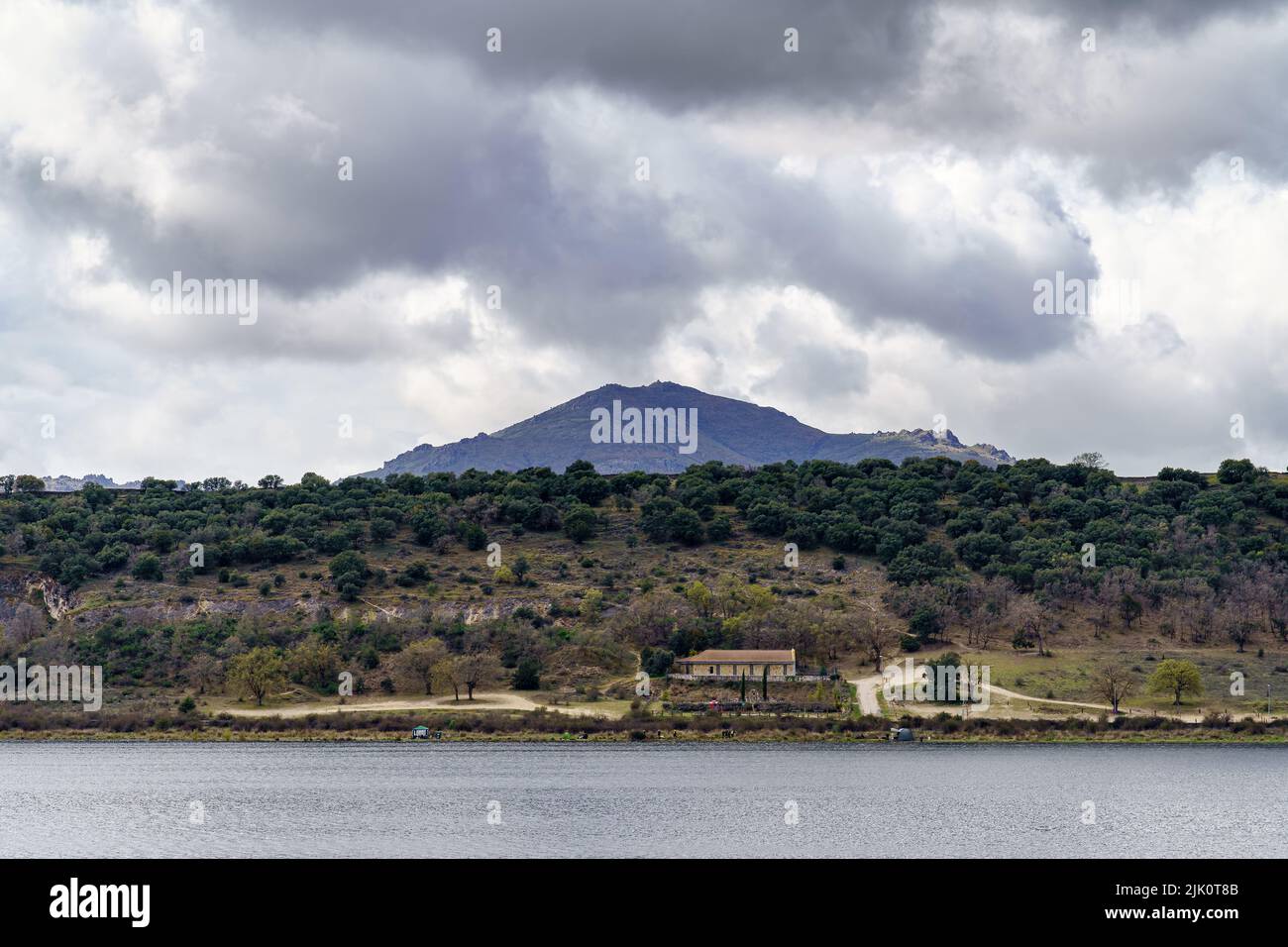 Mountain and forest next to the blue lake with dark clouds that seem to ...