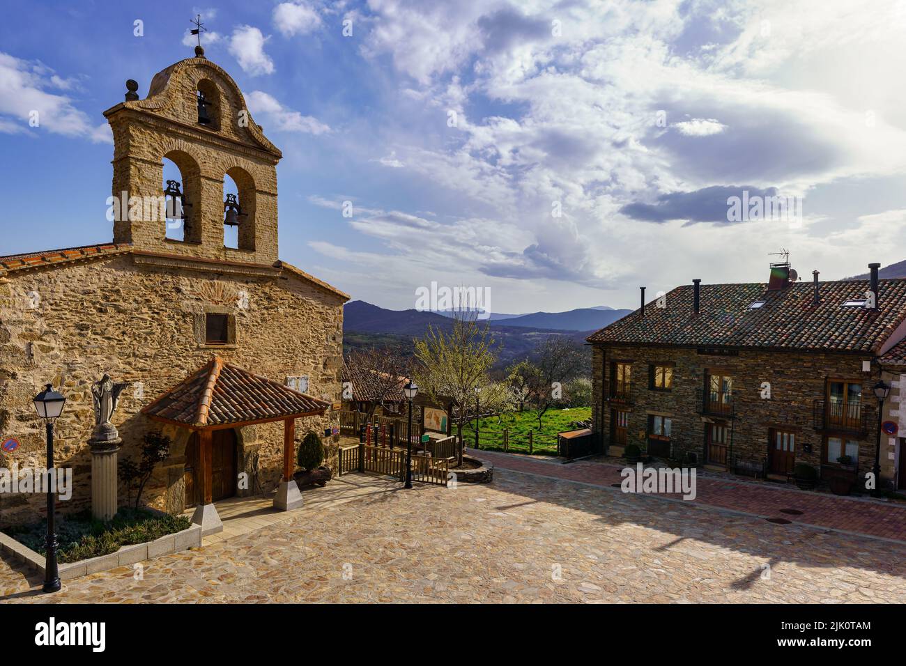 Ancient stone church in medieval village with old houses and blue sky ...
