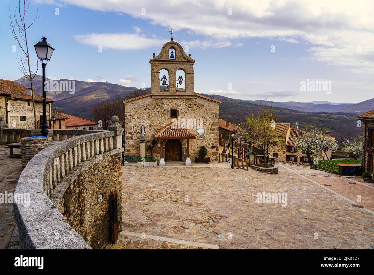 Ancient stone church in medieval village with old houses and blue sky ...