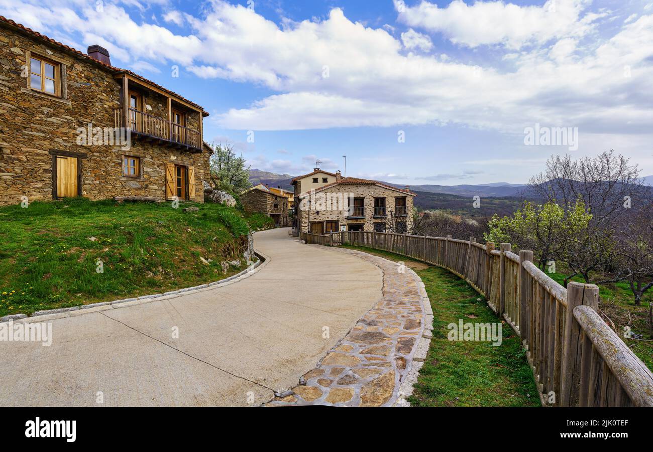 Old town street with curved street and wooden fence next to the garden ...