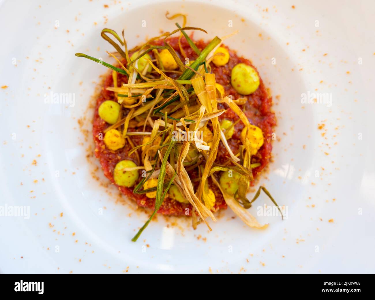 Beef Tartare with Saffron and Leek and Salted Almond on a white Plate ...