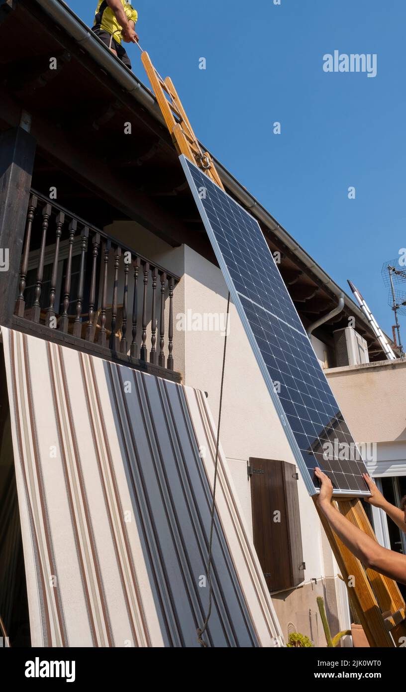 worker lifting solar panel up ladder to rooftop. Navarre, Spain, Europe ...