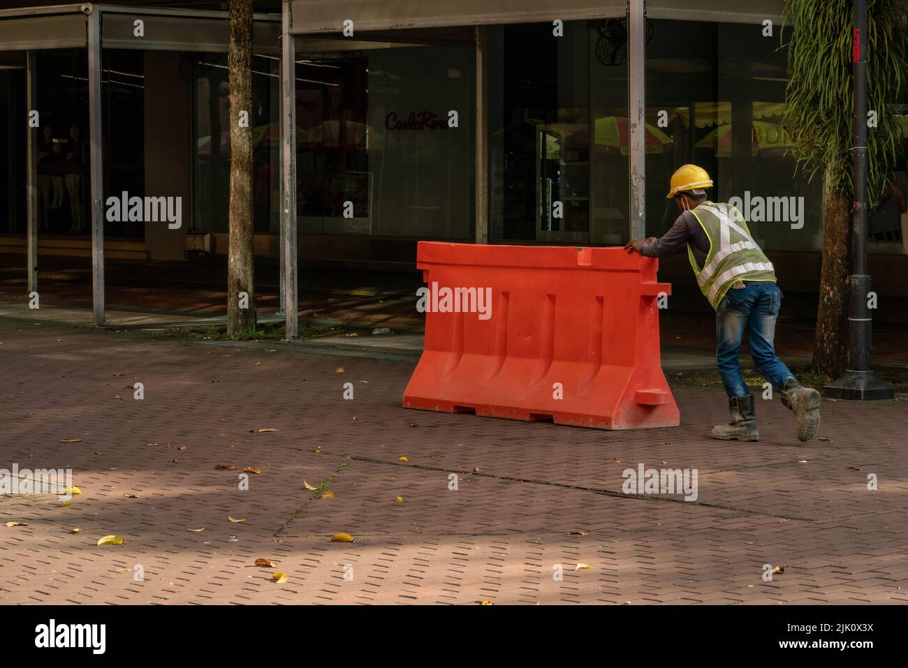 A construction worker pushing a water-filled barricade outside OG Albert Complex, Singapore ...