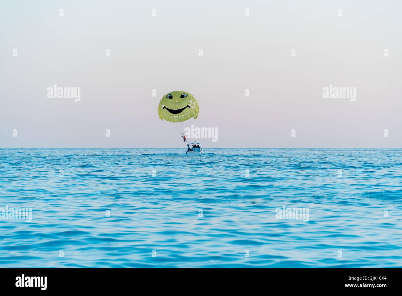 A green parachute with a smiley face and a boat in the sea Stock Photo ...