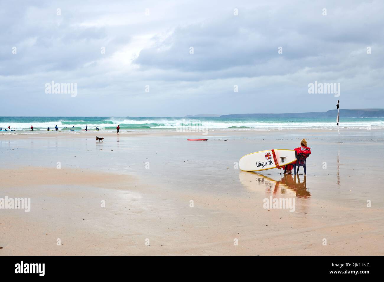 A female lifeguard with surf board on duty, with the tide out ,at the ...