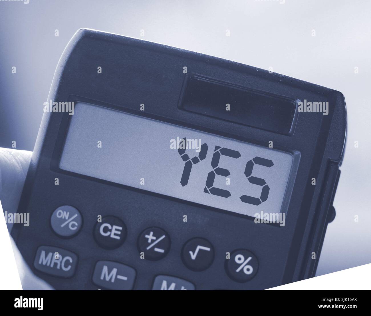 Calculator with YES on display on blue blured background. Positive ...