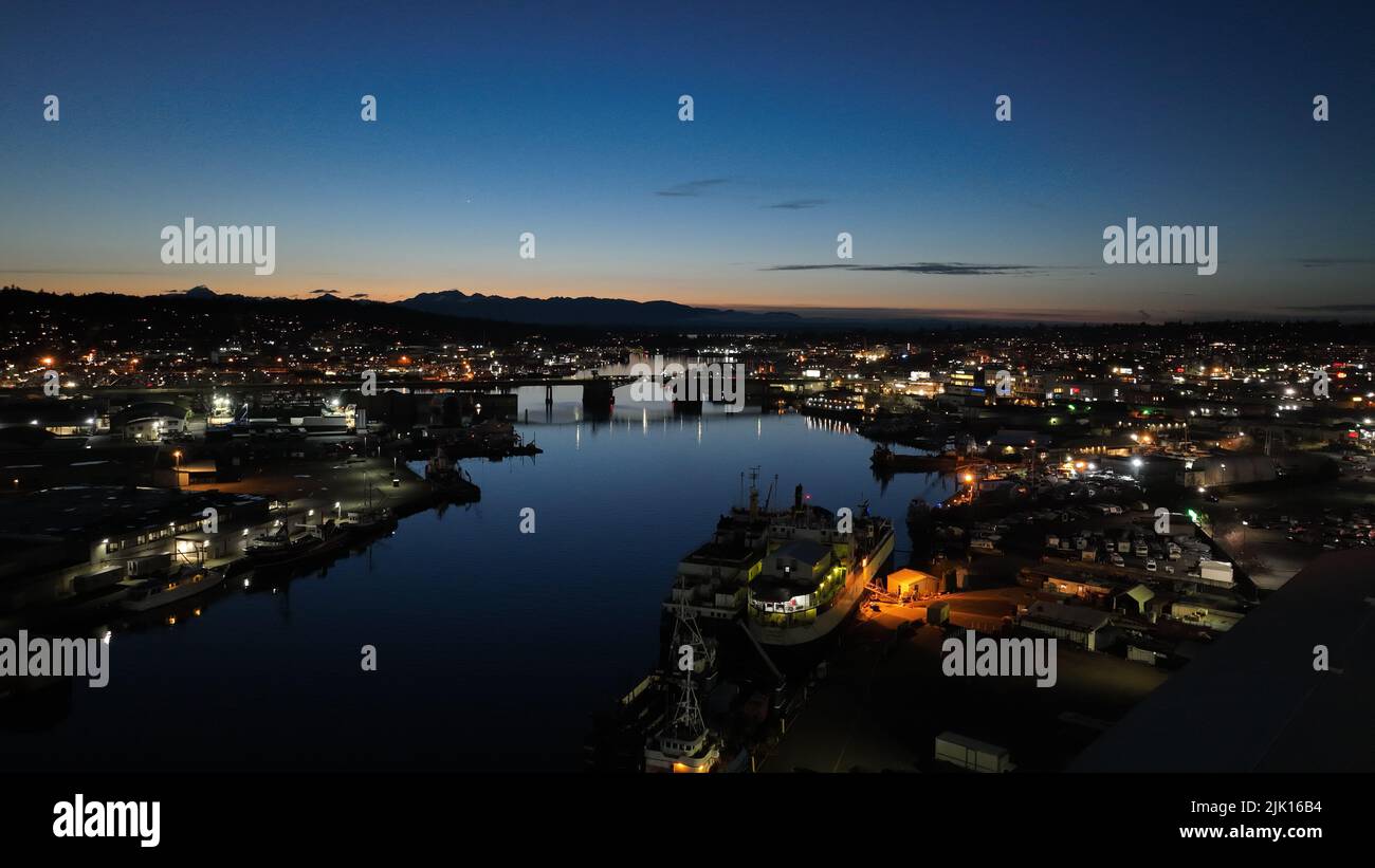 An aerial view of a city with buildings and a port illuminated at night ...