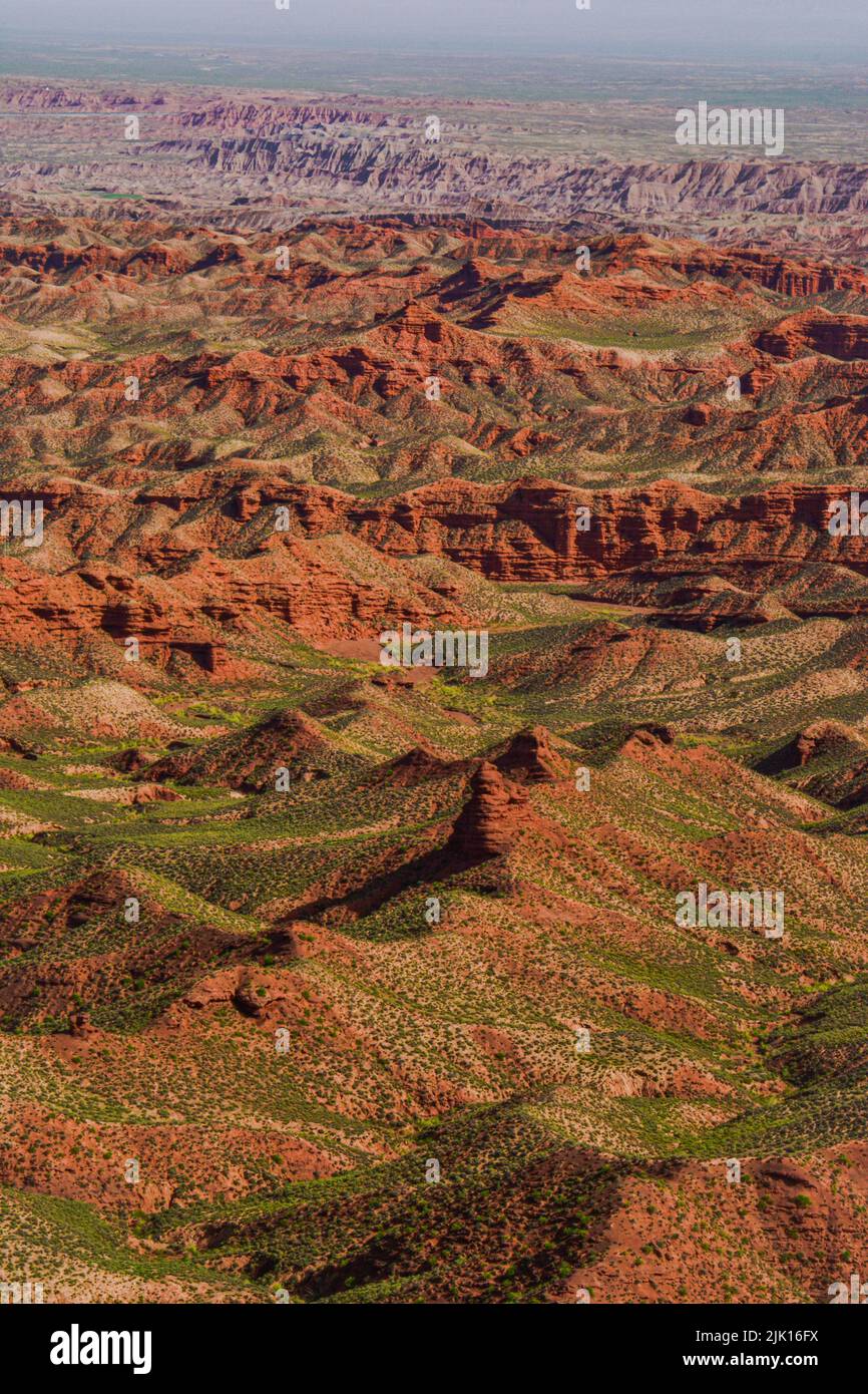 A vertical shot of range rocky desert with green surface with blue sky ...