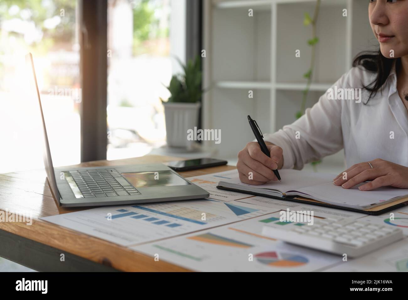 business woman taking note and using laptop for accounting financial ...