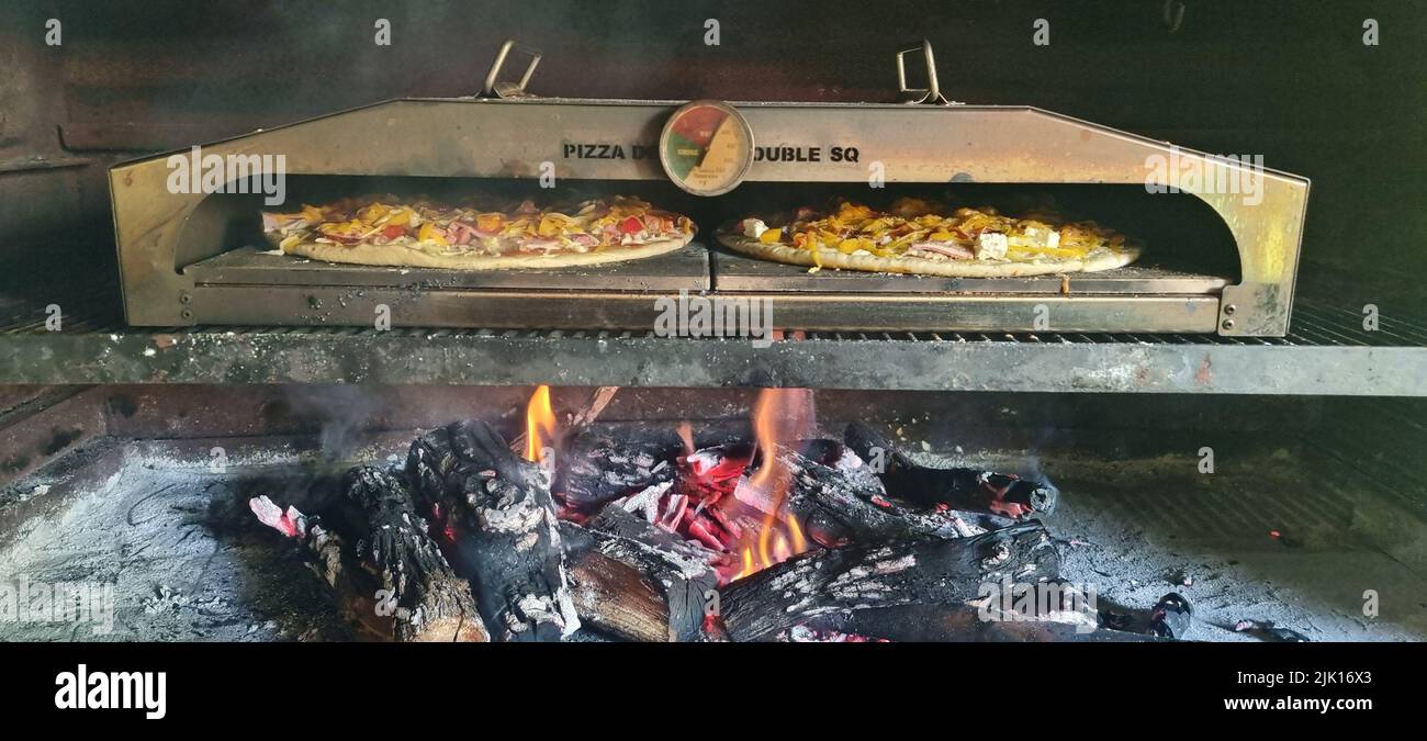 Pizza baking in open fire stainless steel pizza oven Stock Photo - Alamy
