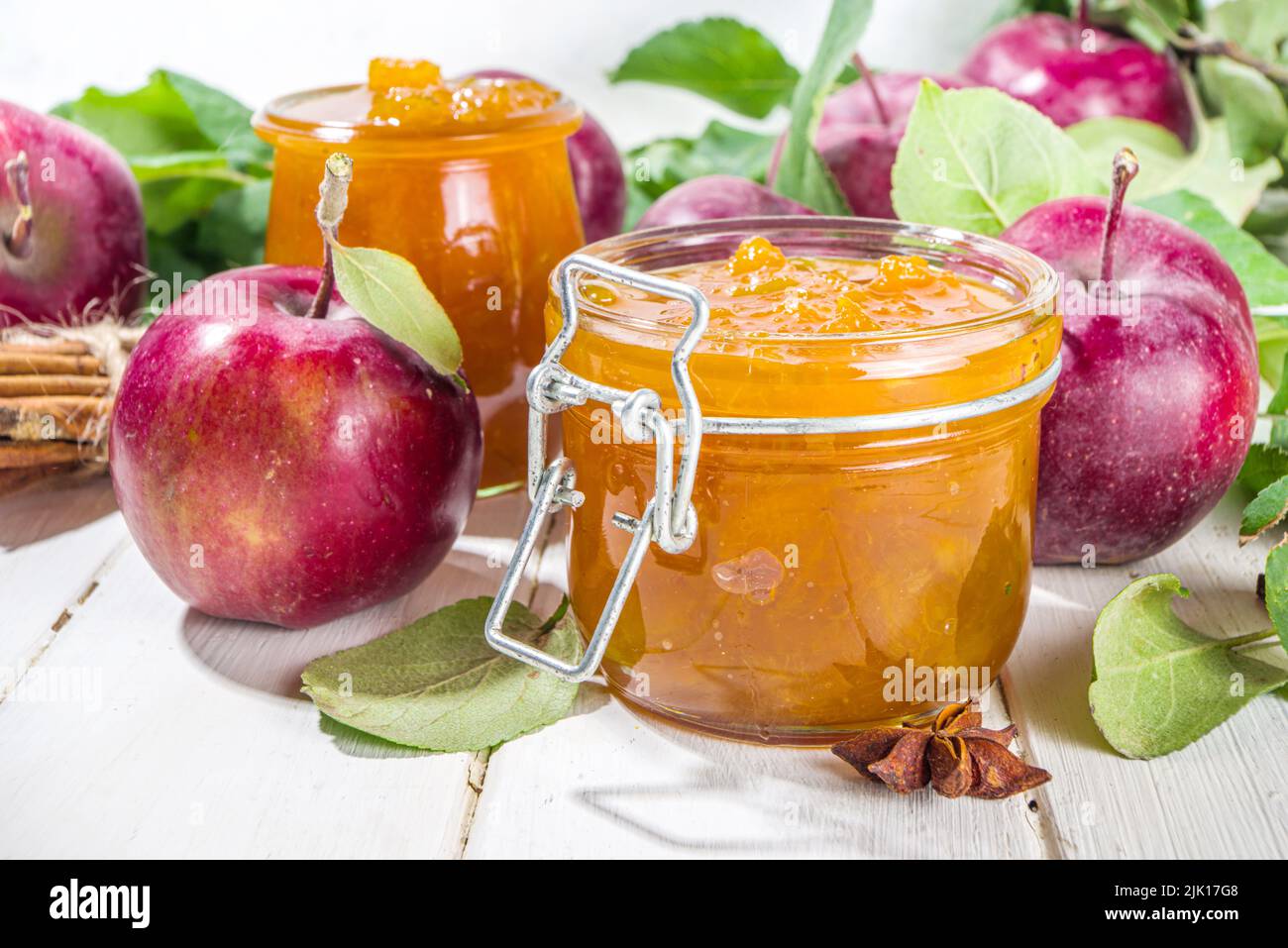 Homemade golden colored apple jam, with farm red apples and leaves on ...