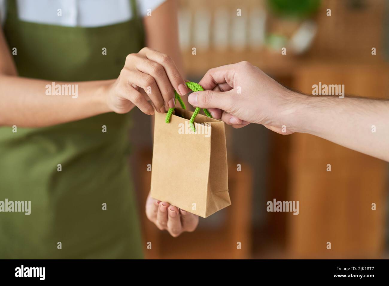 Saleswoman giving paper-bag with ogranic cosmetics to customer Stock ...
