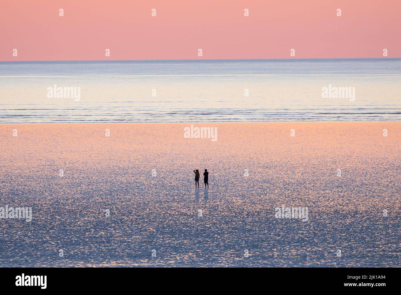 A couple are enjoying the beautiful sunset view at 80 mile beach, in ...