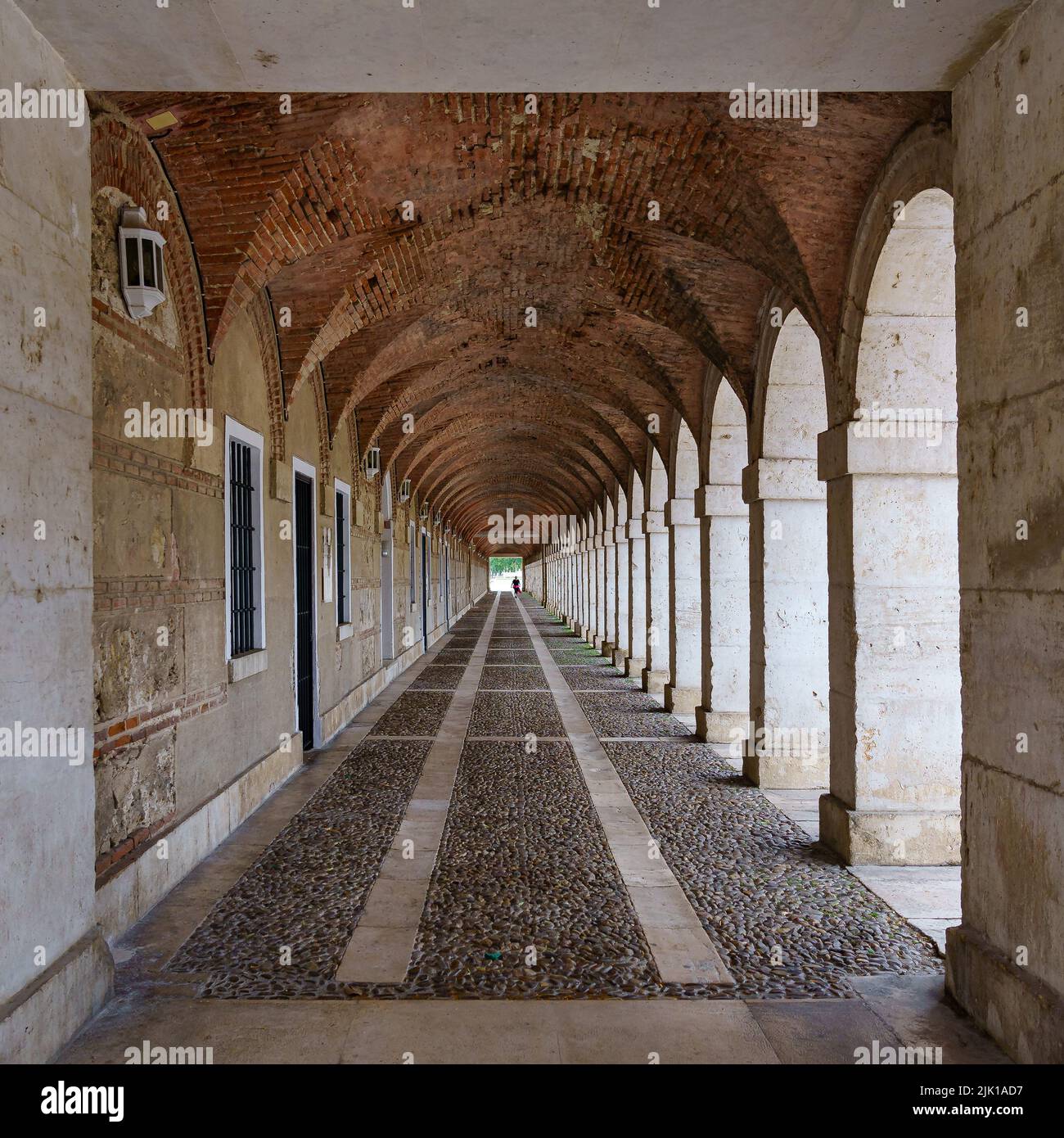 Large symmetrical exterior corridor with arches and columns in the old ...