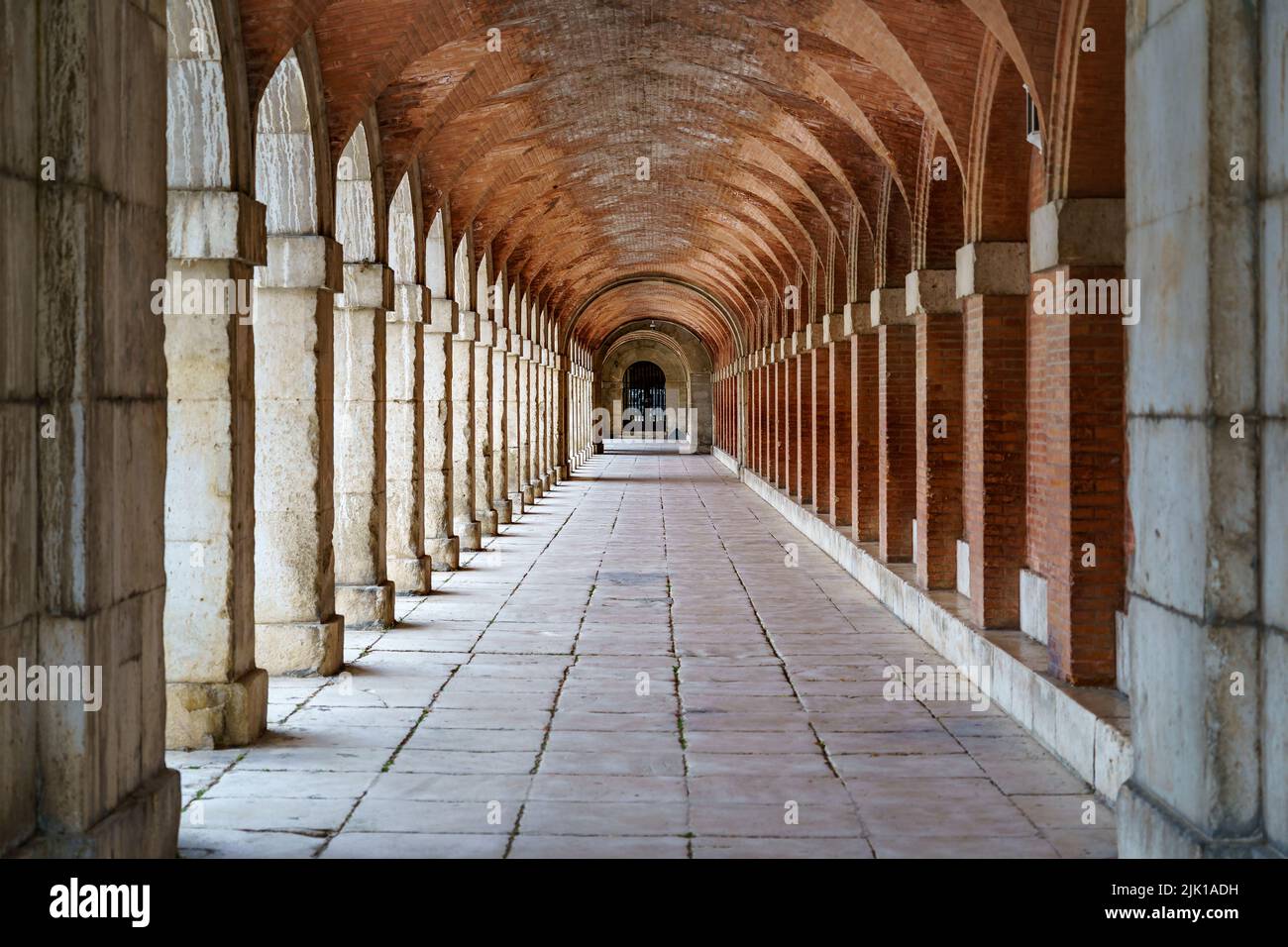 Large symmetrical exterior corridor with arches and columns in the old ...