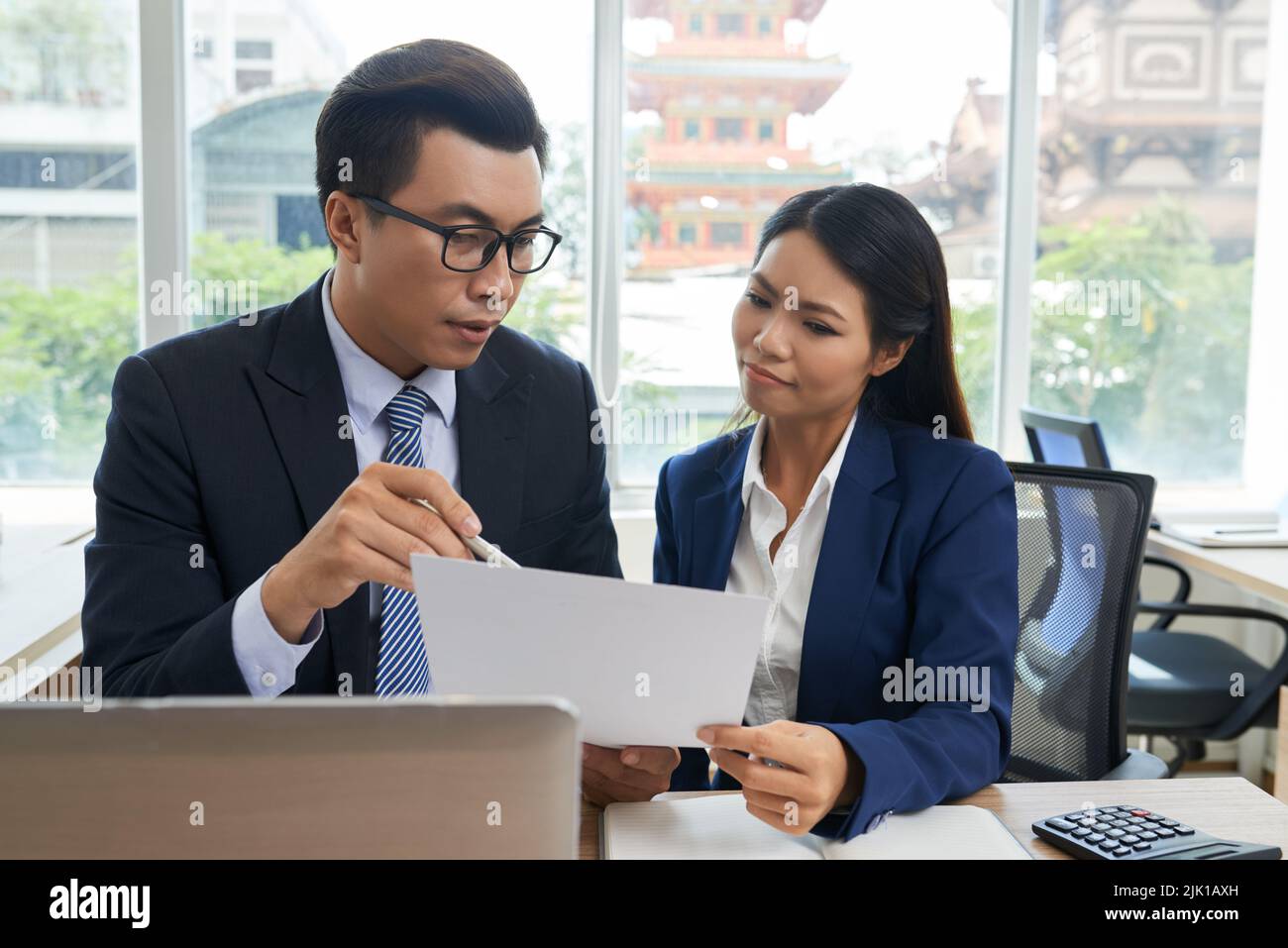 Vietnamese businessman explaining data in document to coworker Stock ...