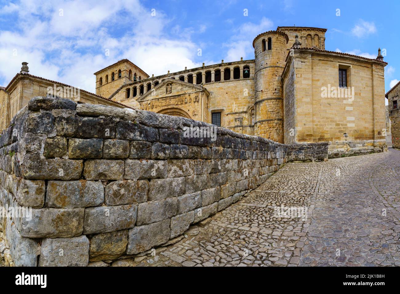 Panoramic of old stone Romanesque church with cobblestone pavement and ...