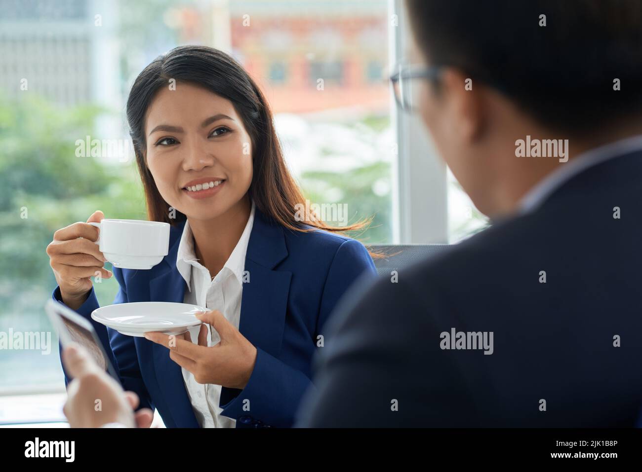 Pretty Vietnamese business lady drinking tea when having meeting with ...