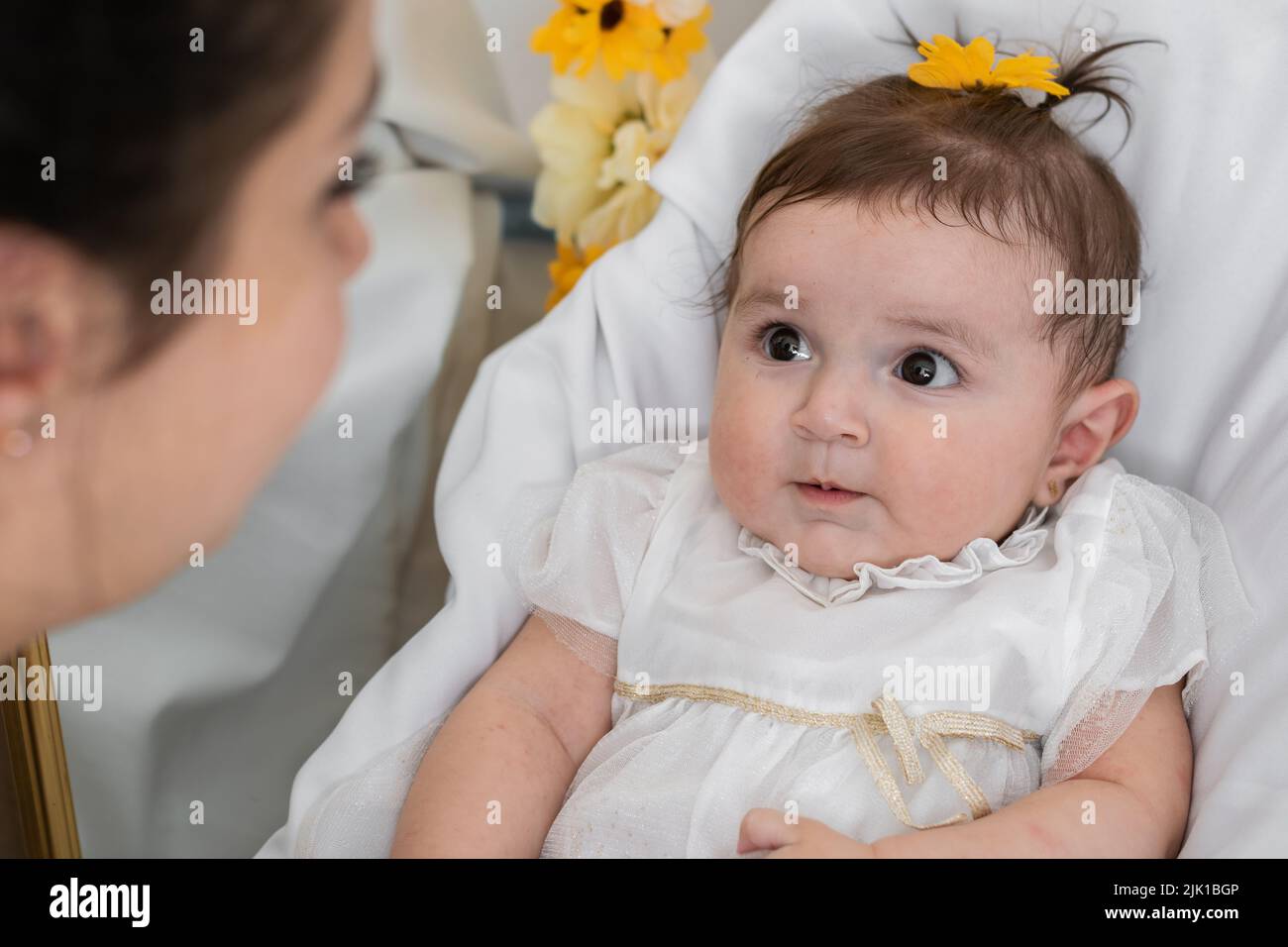 beautiful dark eyed latina baby lying on her crib looking at her mother ...