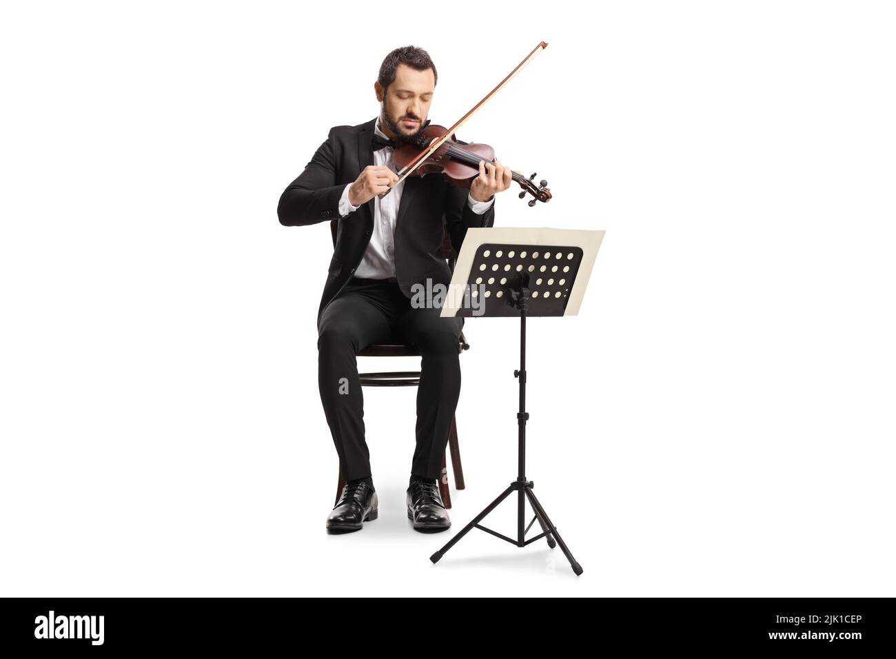 Full length portrait of an elegant man sitting and playing a violin ...