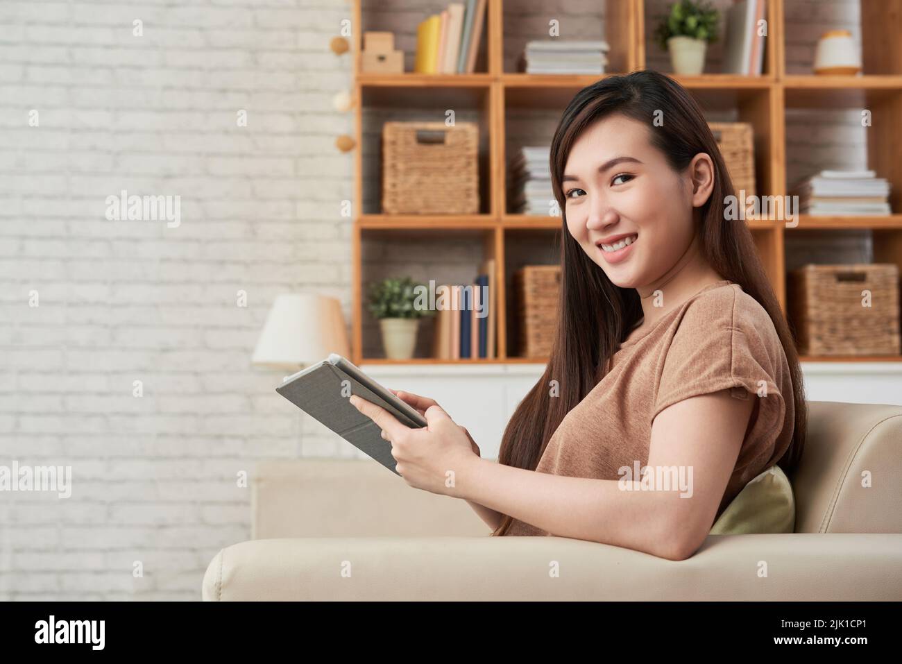 Portrait of smiling Vietnamese woman with tablet computer resting on ...