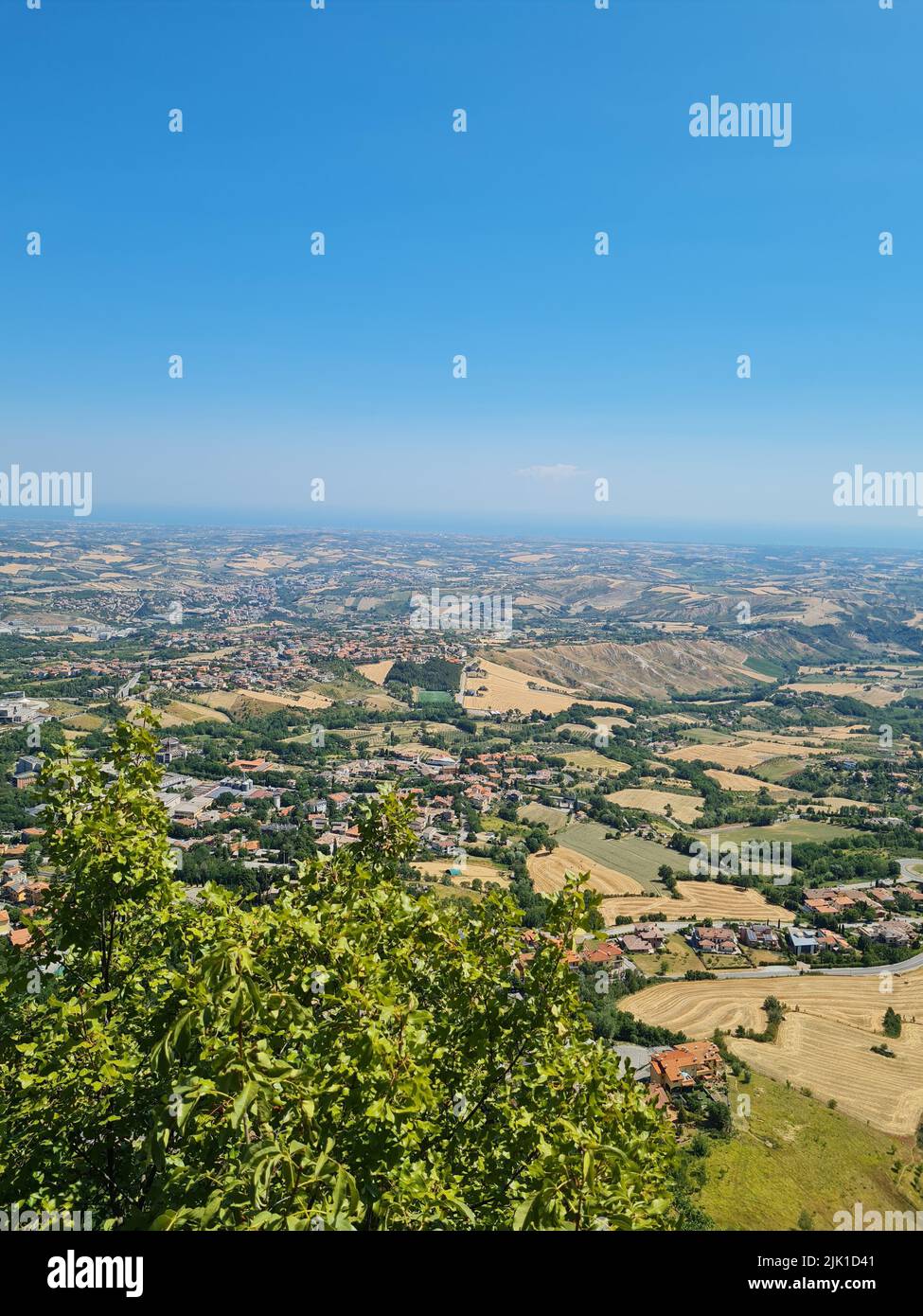 A beautiful view from a high point of a green landscape with cliffs and houses under blue sky ...