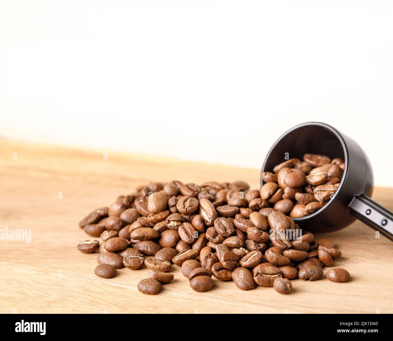 Coffee beans spilling from scoop Stock Photo - Alamy
