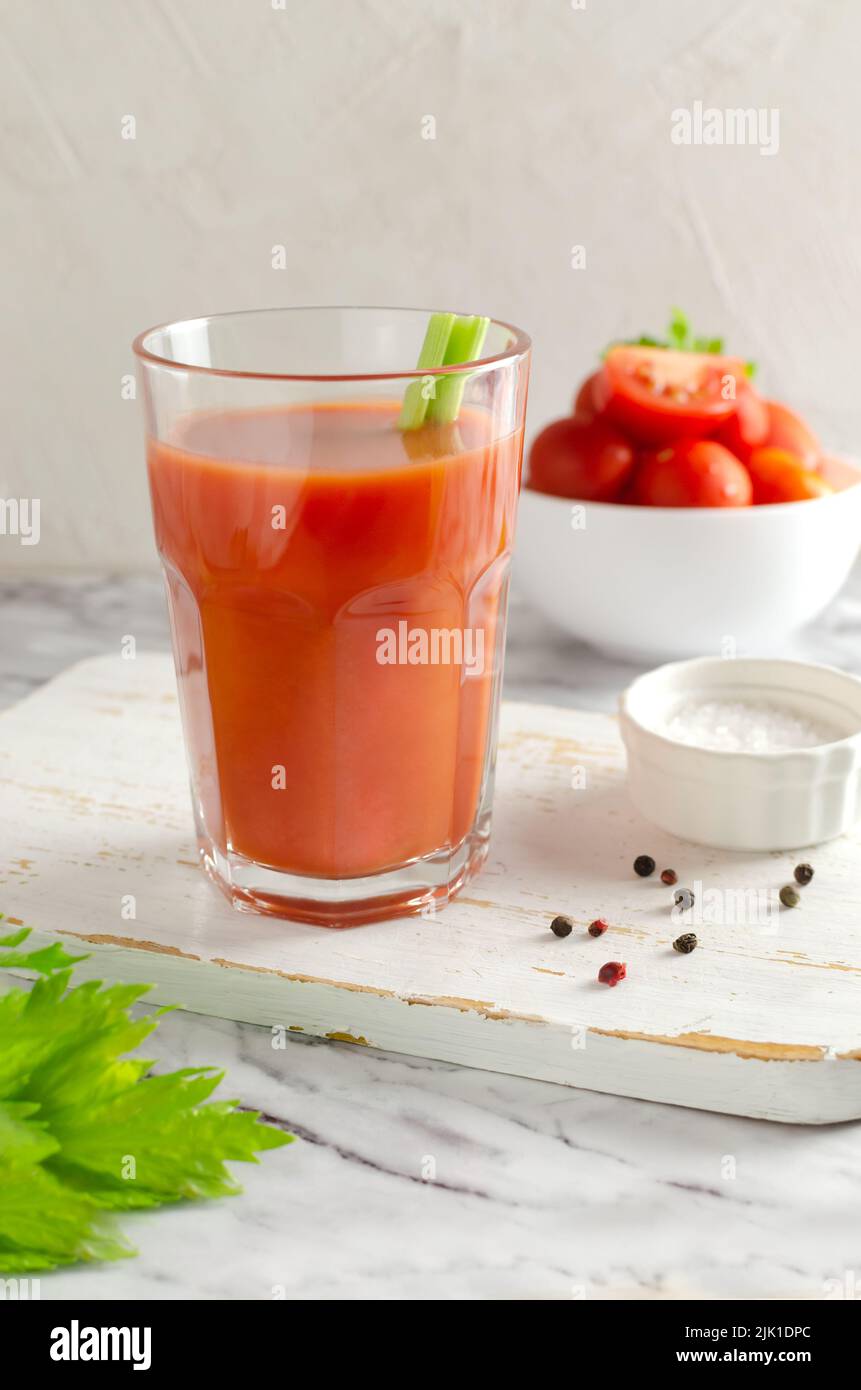 One transparent glass cup with red tomato juice and a sprig of celery ...