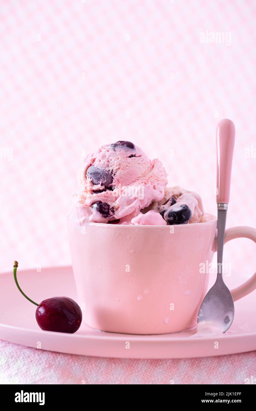 Scoops of black cherry ice cream in a pink cup featuring a pink color ...