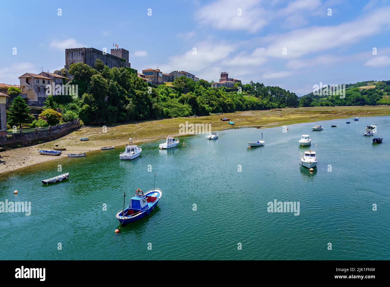 Sea estuary under the medieval castle with small boats anchored. San ...