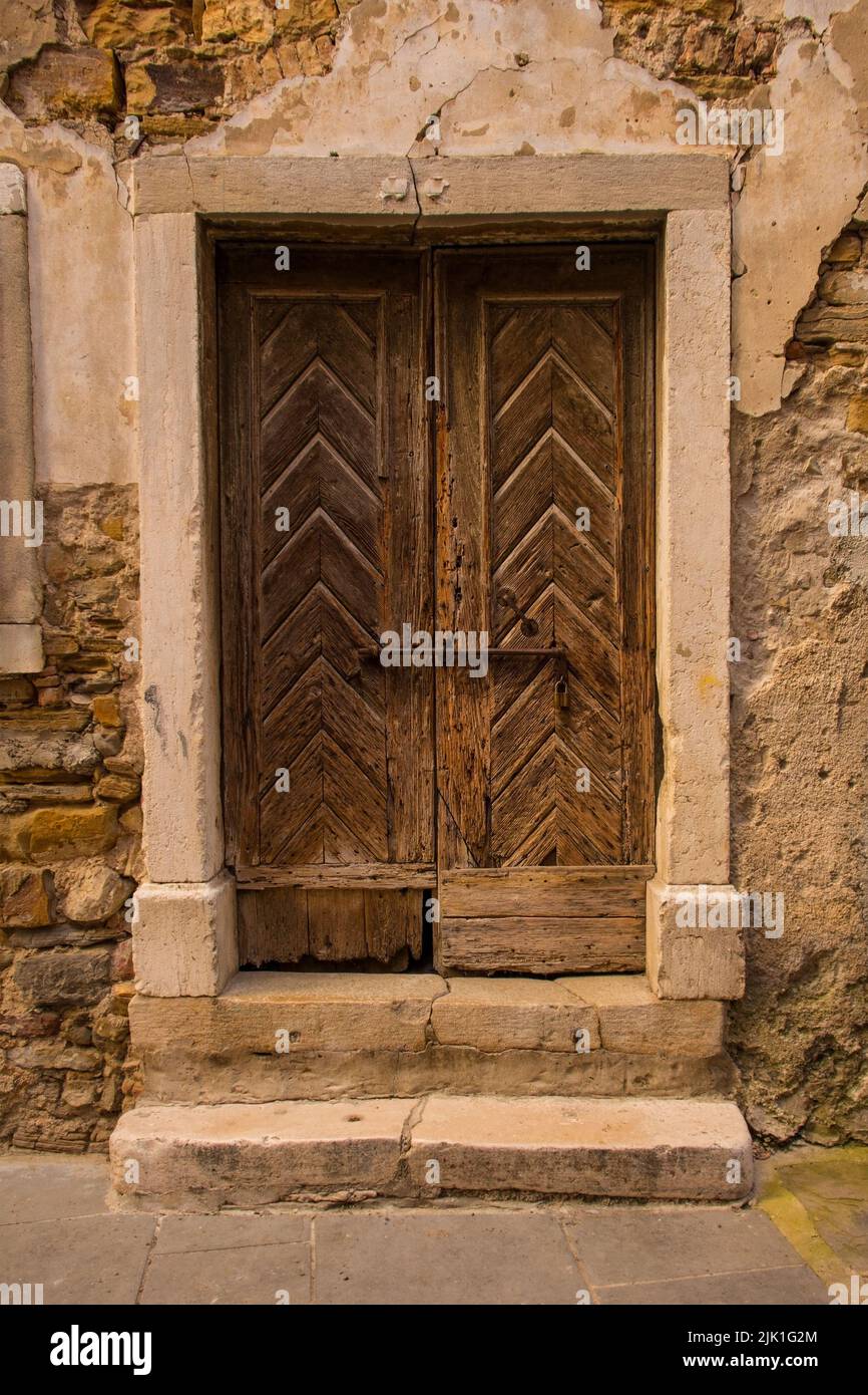 An old wooden door in a derelict stone building in the medieval centre ...