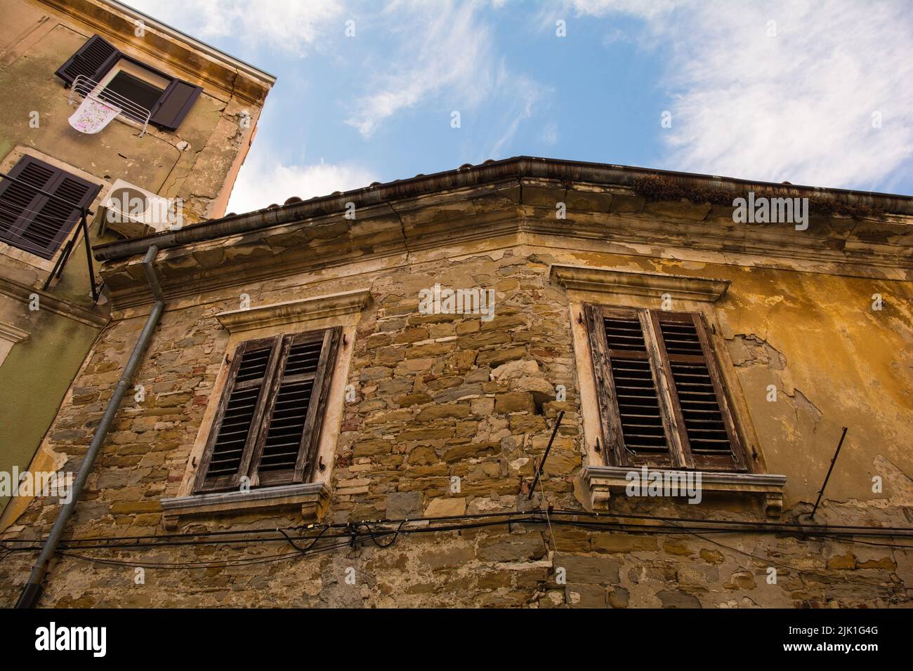 Shuttered windows in a derelict stone residential building in the ...