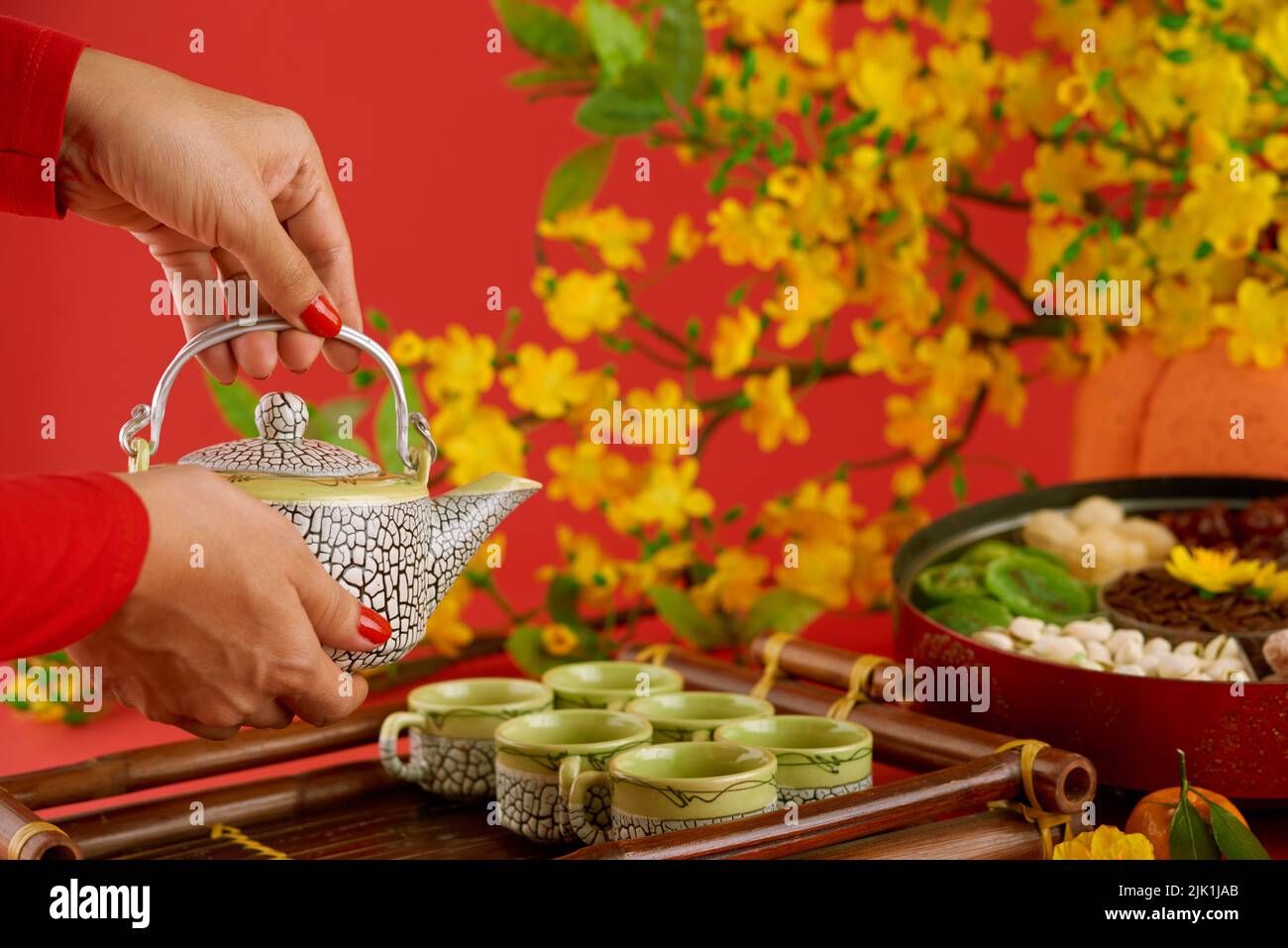 Hands of woman pouring green tea to the cups on table served for Tet ...