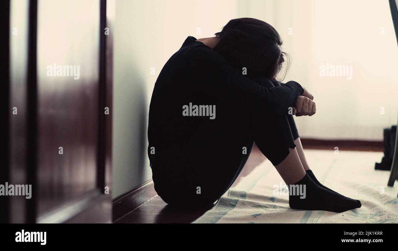 Fearful depressed person sitting on floor covering face in fetal ...