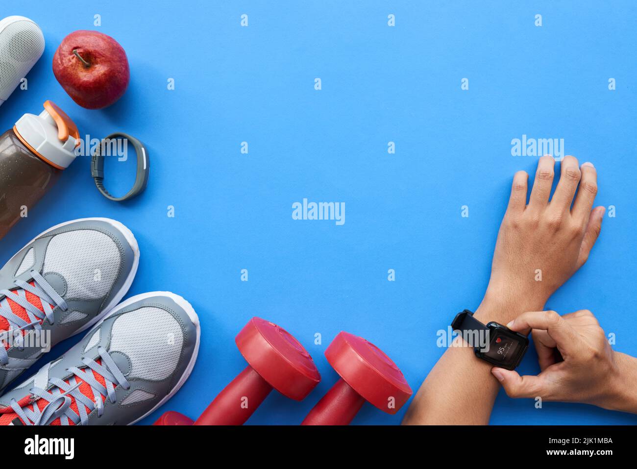 Flat lay of sport equipment and man checking heart rate on his smart ...