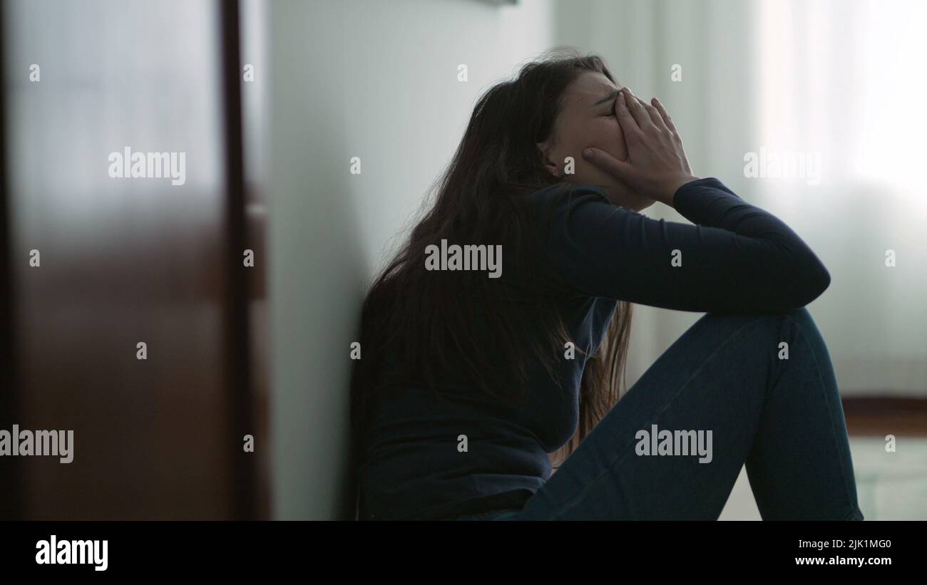 Anxious woman sitting on floor suffering from mental illness at home ...