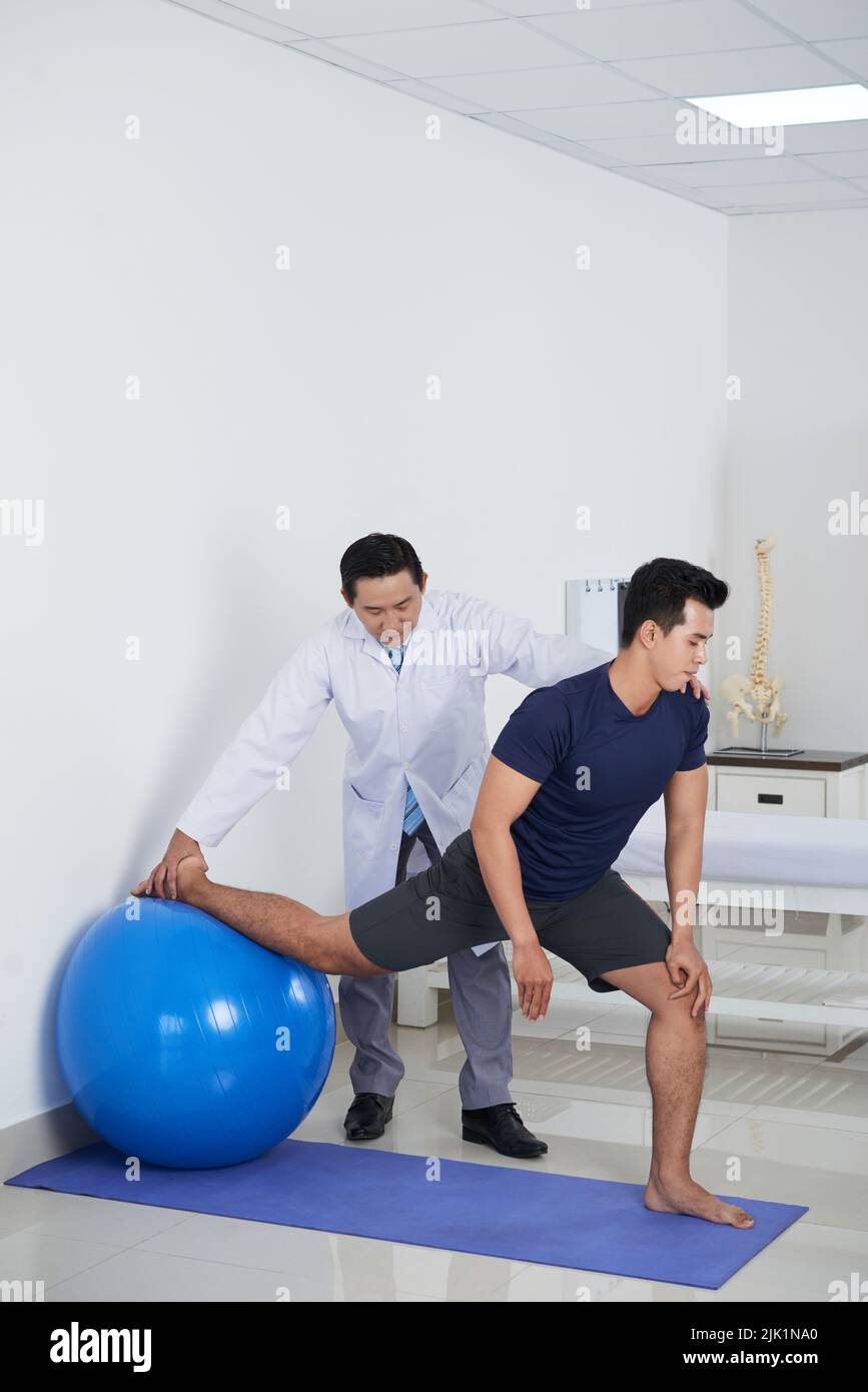 Physiotherapist helping patient to do exercise on fitness ball Stock ...