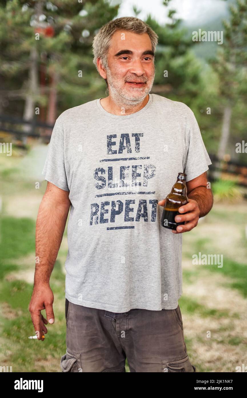 Handsome man with gray hair, hold in his hands cigarette and beer ...