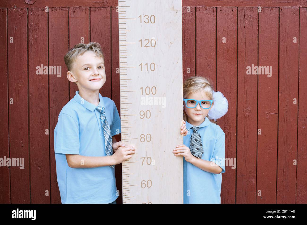 girl and schoolboy with big ruler standing on wood background Stock ...