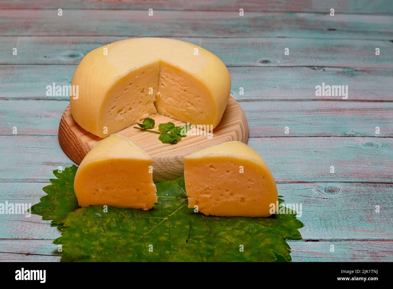 Round white homemade goat milk cheese on vine leaf on a wooden table ...