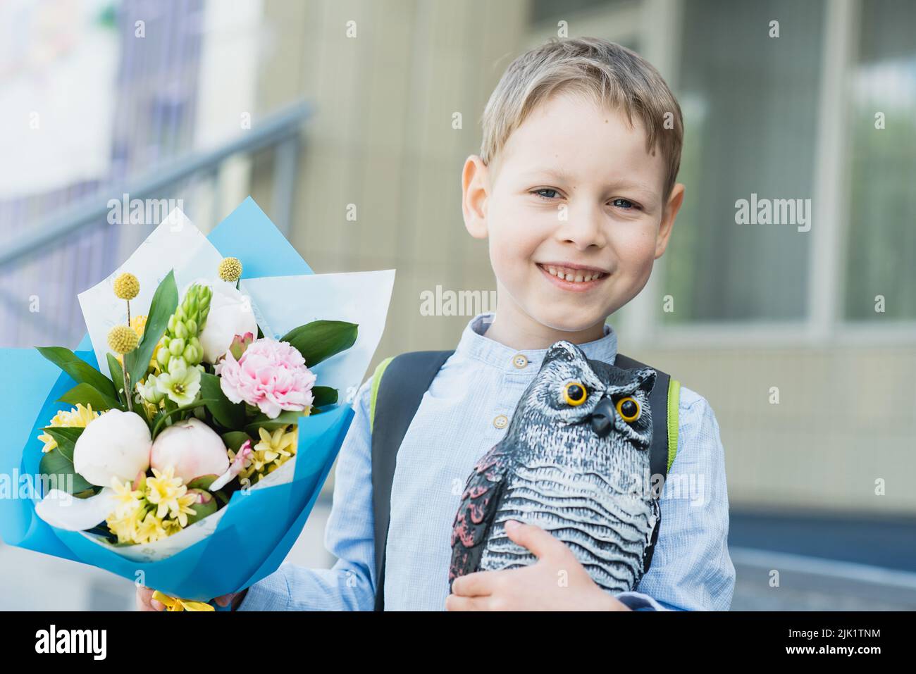 Portrait of a beautiful young first-grader with bouquet in a school ...