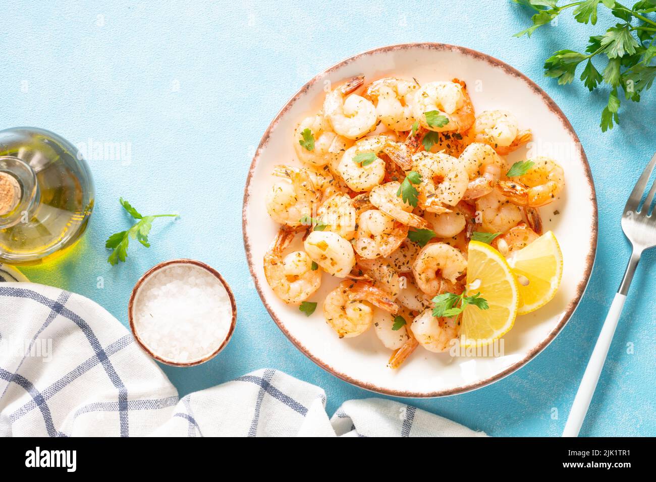 Fried shrimps with herbs and olive oil at blue table Stock Photo - Alamy