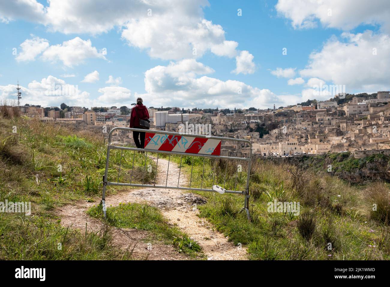 A woman hiking a closed path through the canyon of Matera, Southern ...