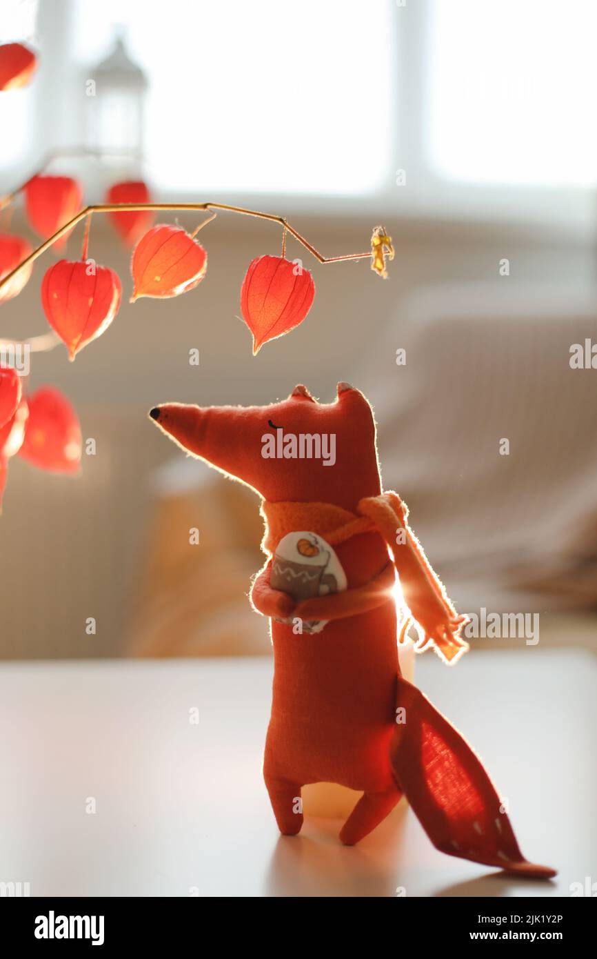 autumn still life with a toy fox, flowers, twigs of red physalis in a ...