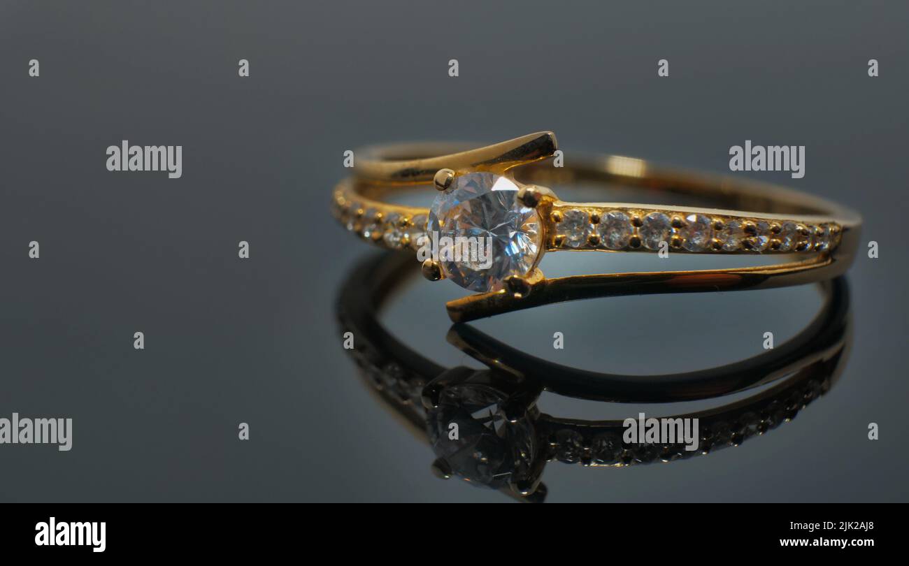 Gold jewelry ring with diamond on reflected black table Stock Photo - Alamy