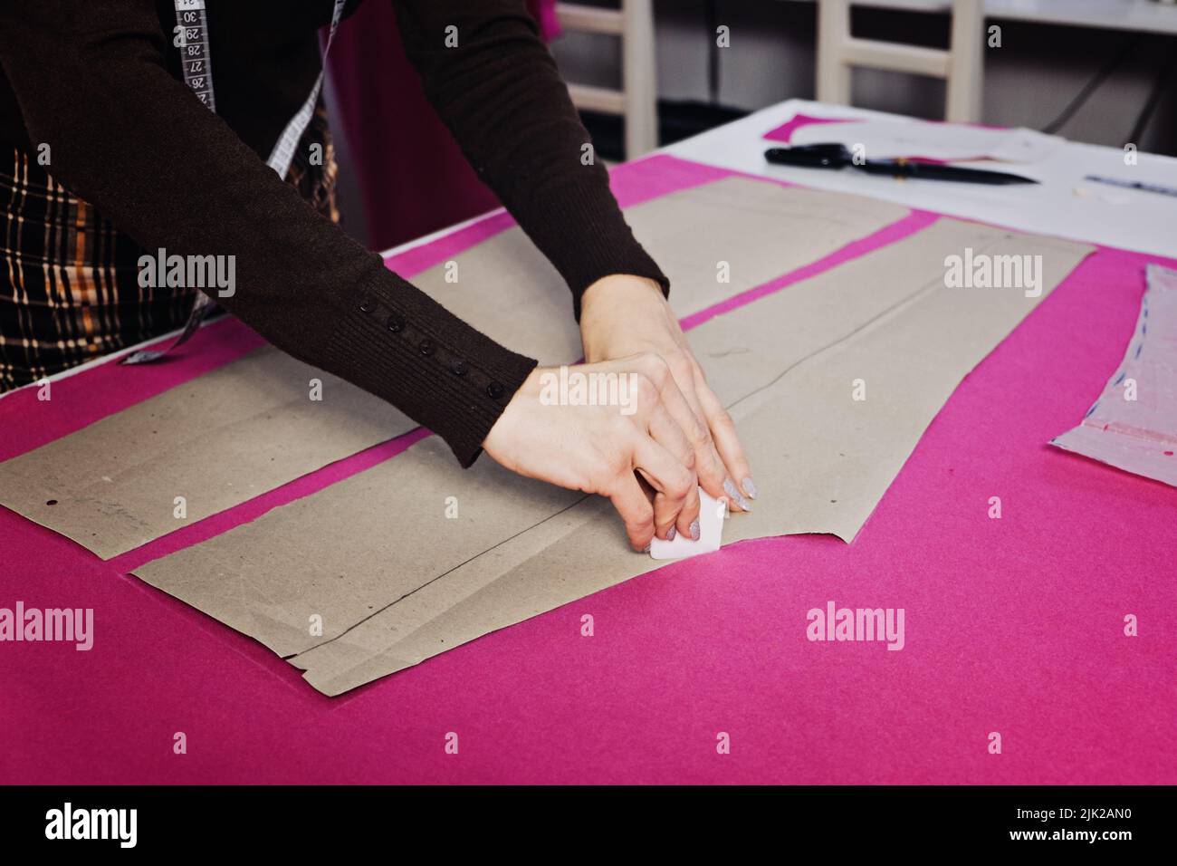 Female fashion designer tailor making sewing patterns at workplace in ...