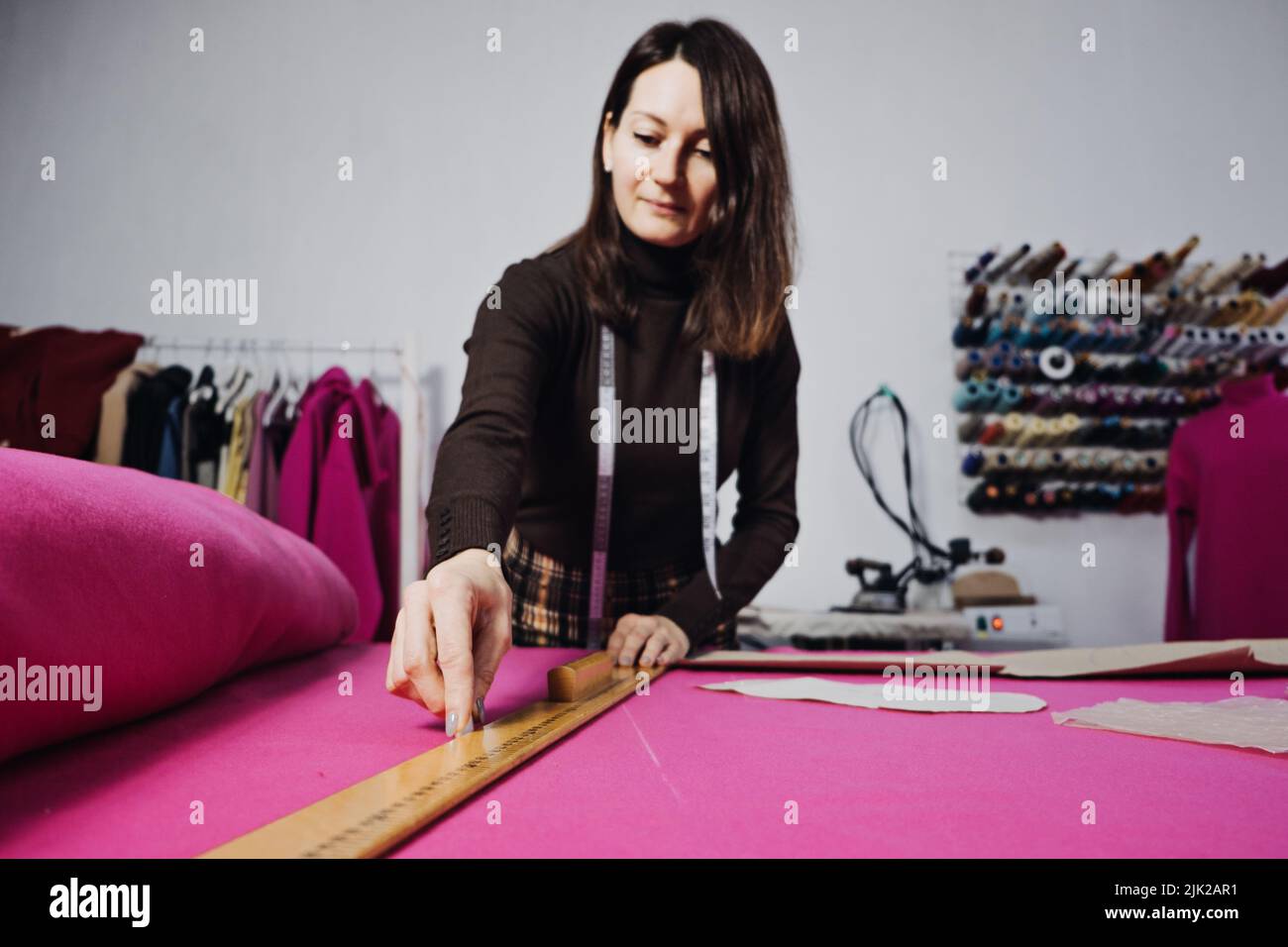 Female fashion designer tailor making sewing patterns at workplace in ...