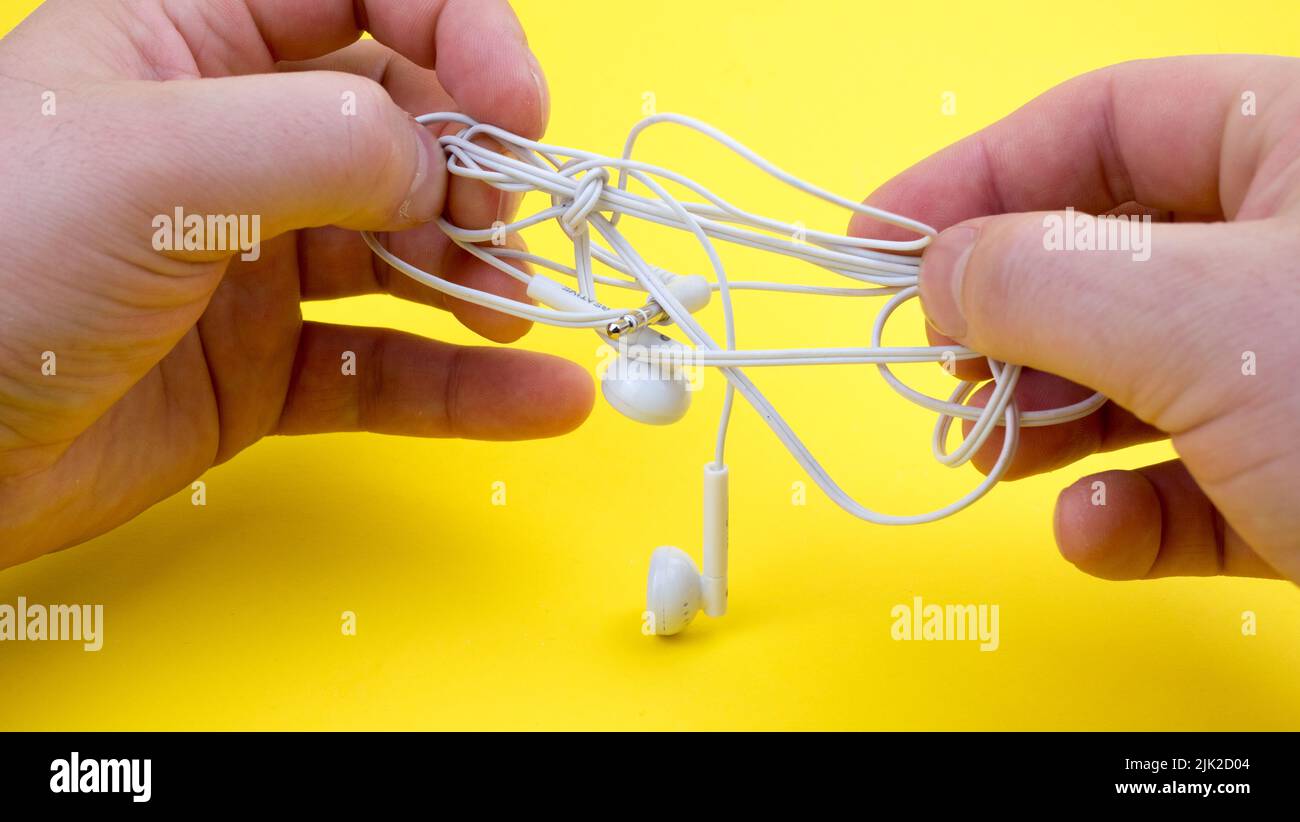 The man hands are trying to untangle the tangled headphones, on a ...